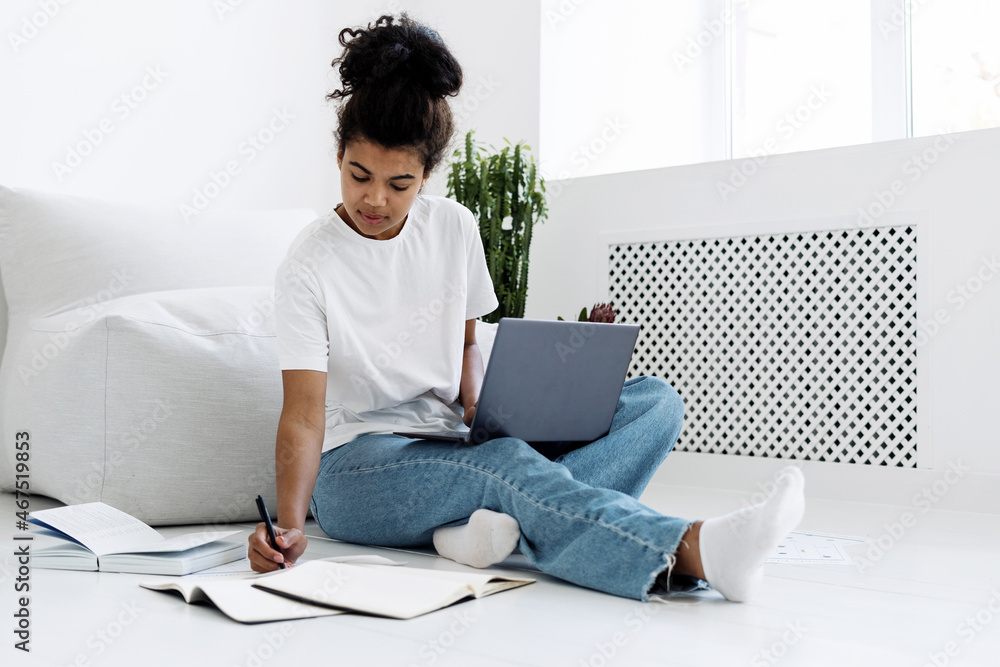 Young student girl with laptop writing in notepad Stock Photo | Adobe Stock