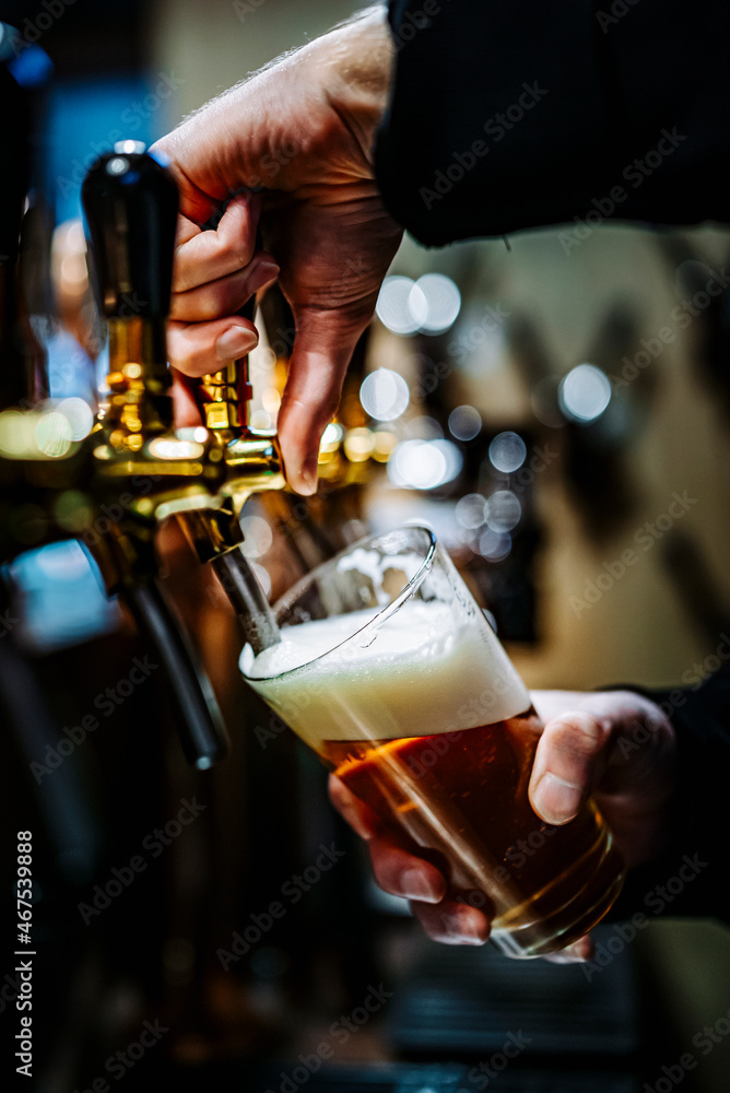 bartender hand at beer tap pouring a draught beer in glass serving in a bar or pub Stock Photo ...