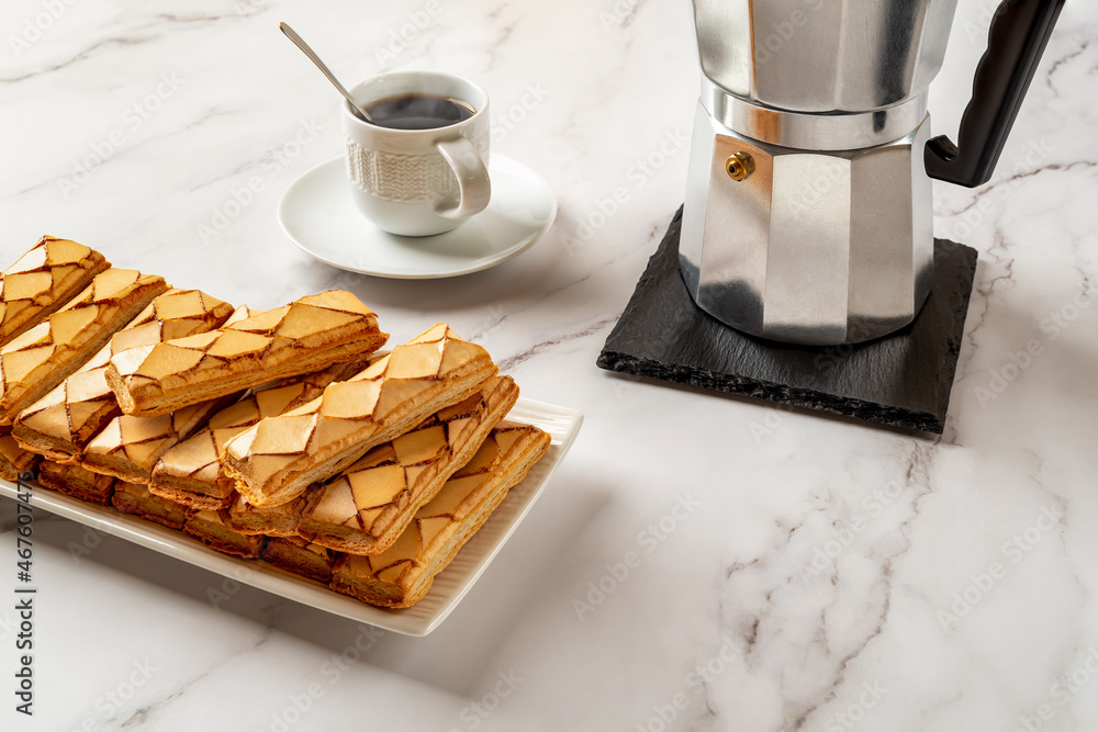 Puff pastries with an apricot glase on a white rectangular plate, cup ...