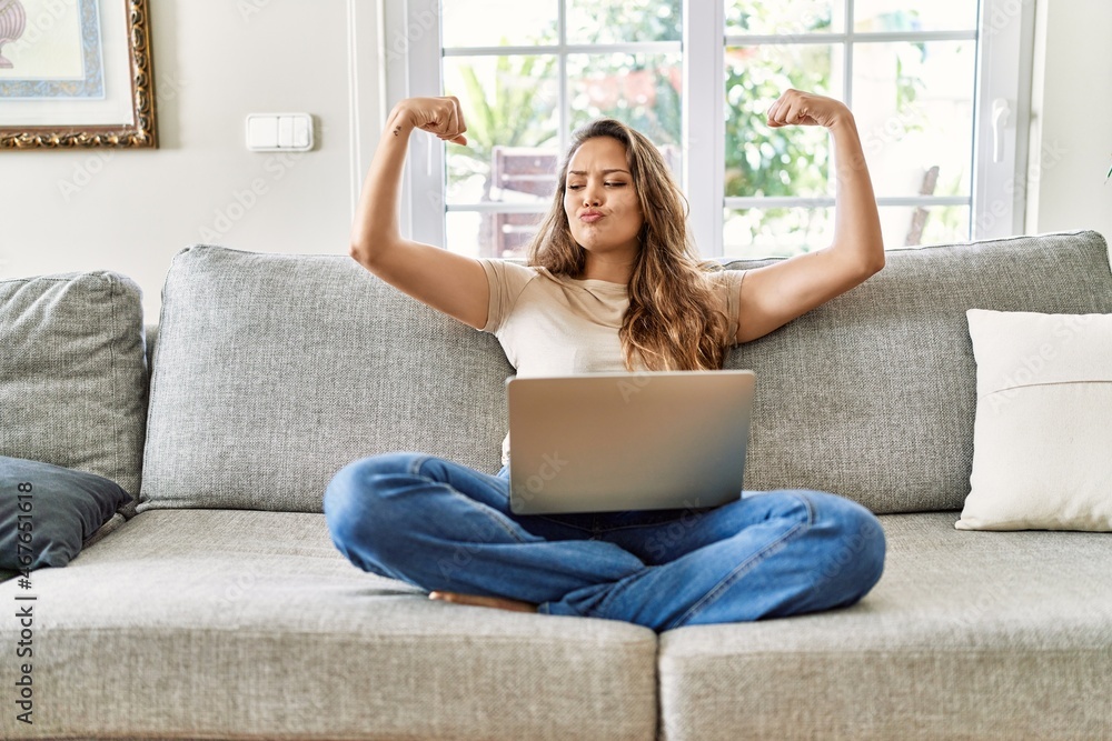 Beautiful young brunette woman sitting on the sofa using computer ...
