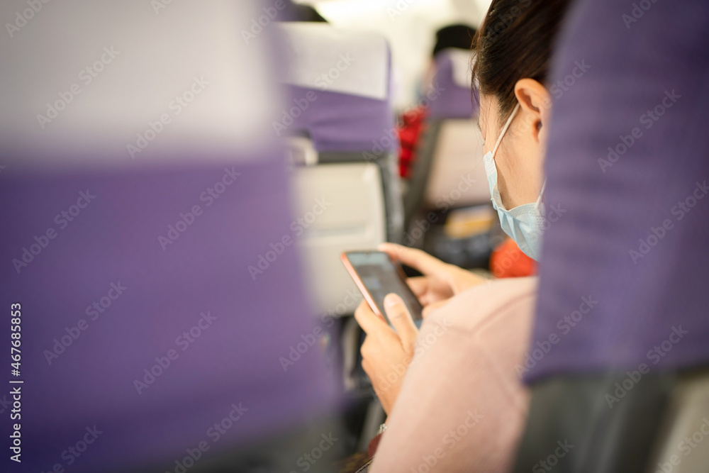 Inside an airplane, focus on a young Asian female passenger on the ...