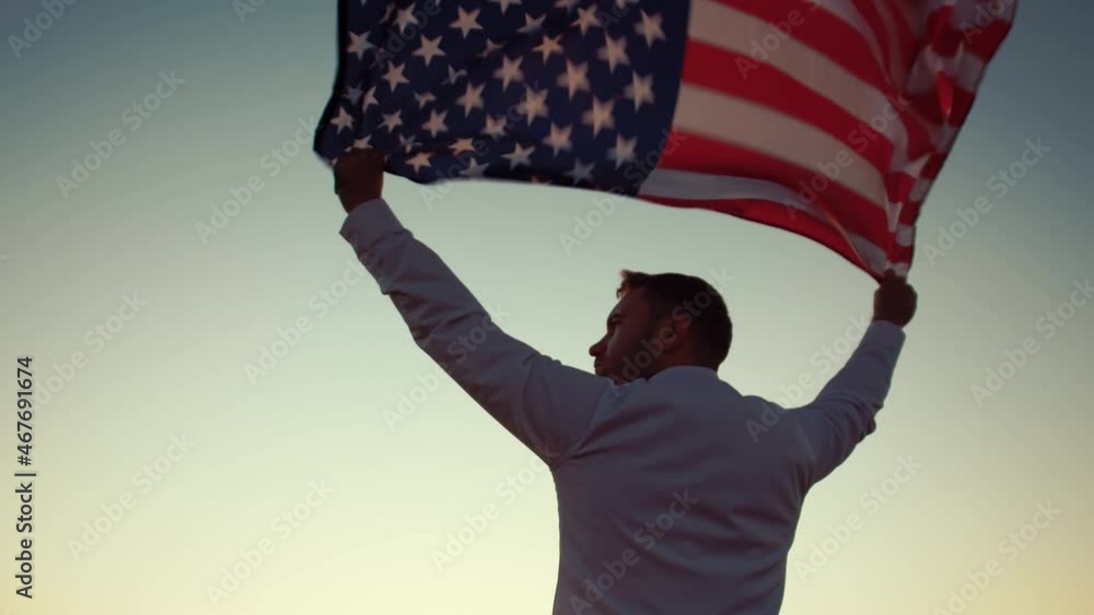 Vidéo Stock Man stands background sky holding an American flag above ...