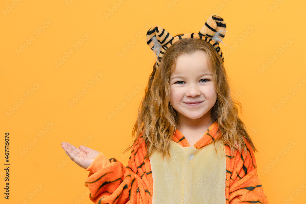 cute smiling girl in tiger costume on isolated yellow background with ...
