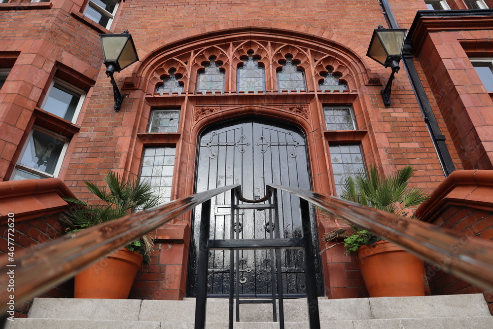 red brick old symmetrical building entrance with double black doors ...