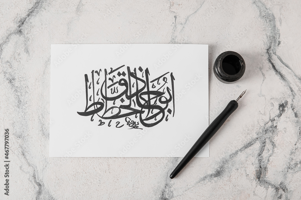 Paper with Arabic text and tools for calligraphy on light background ...