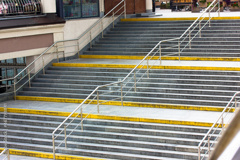 Foto de A wide, modern stone staircase with yellow markings for blind ...