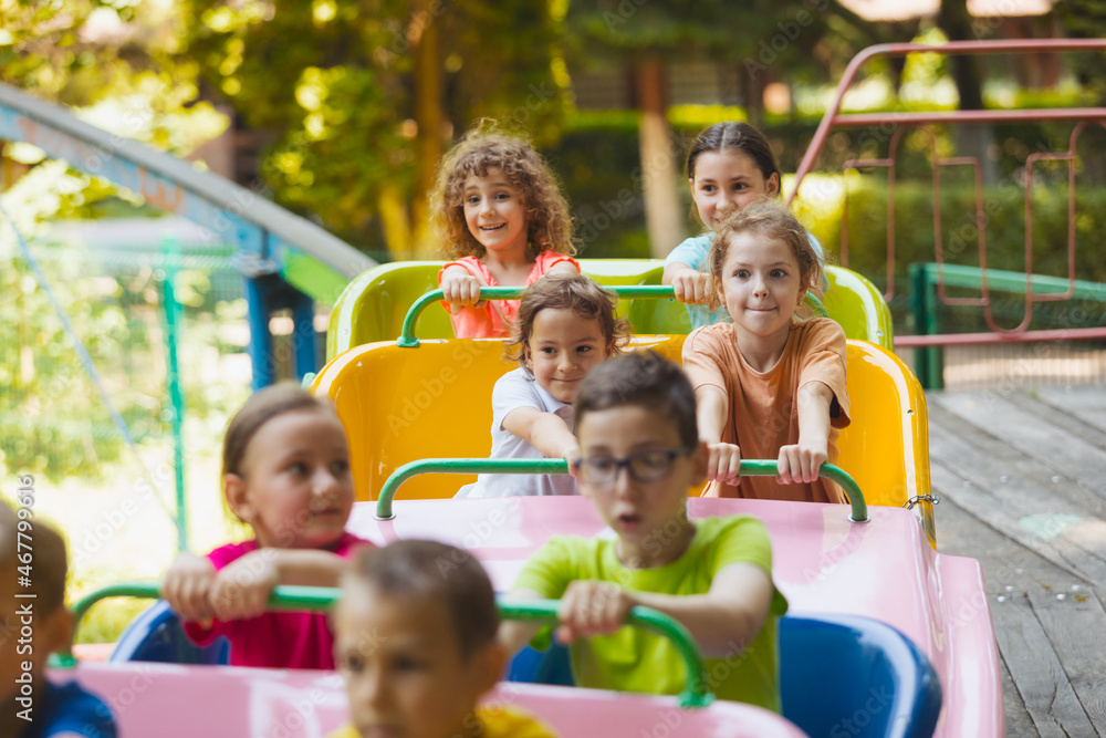 The happy kids on a roller coaster in the amusement park Stock Photo ...