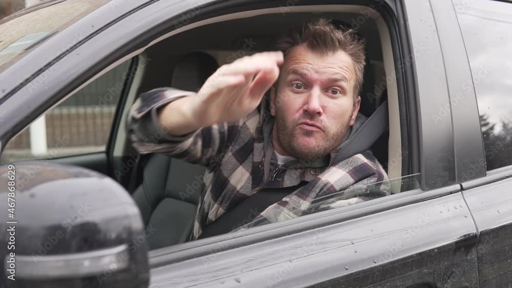 An angry, nervous male driver swears and punches the steering wheel in ...