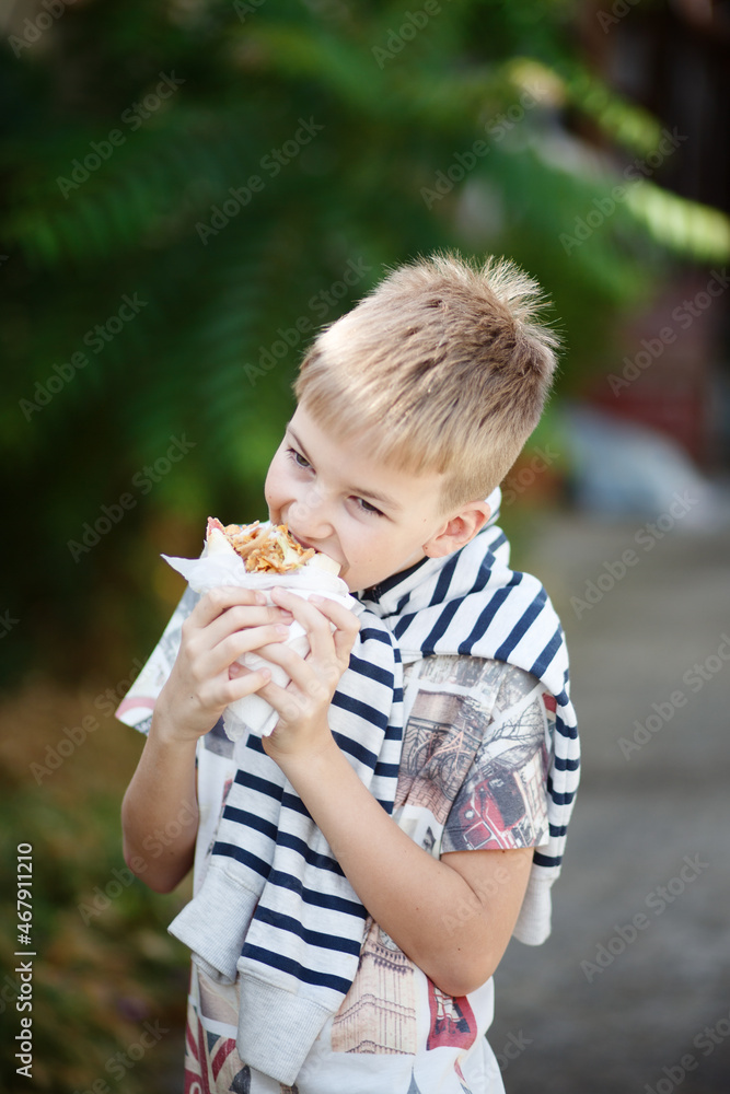 Cute blonde boy eating shrimp roll at fast food restaurant. Unhealthy ...