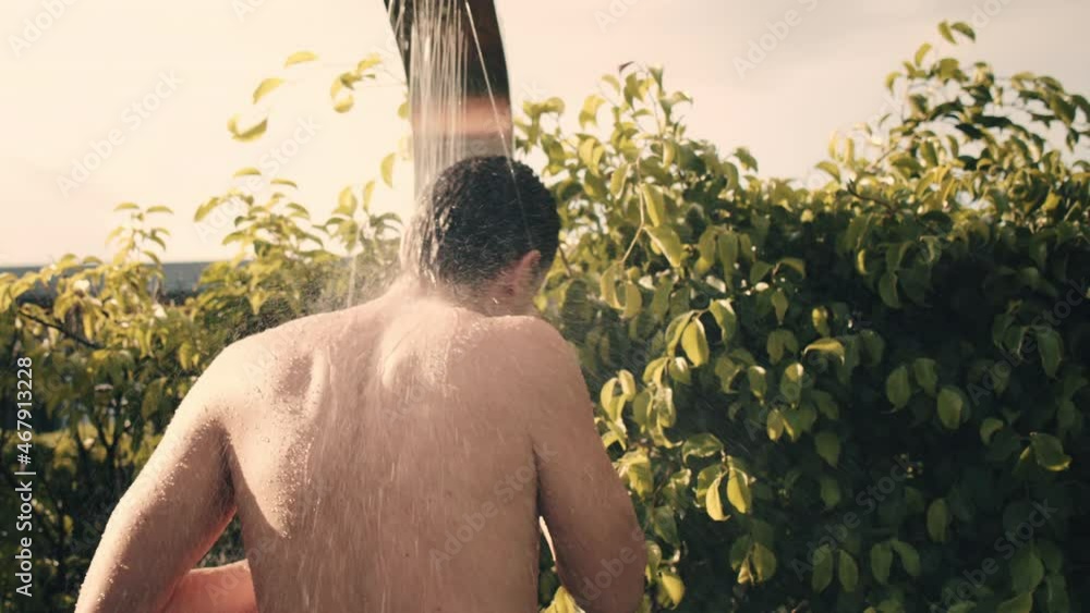 An athlete surfer takes a rain shower after kitesurfing. Shower in a ...