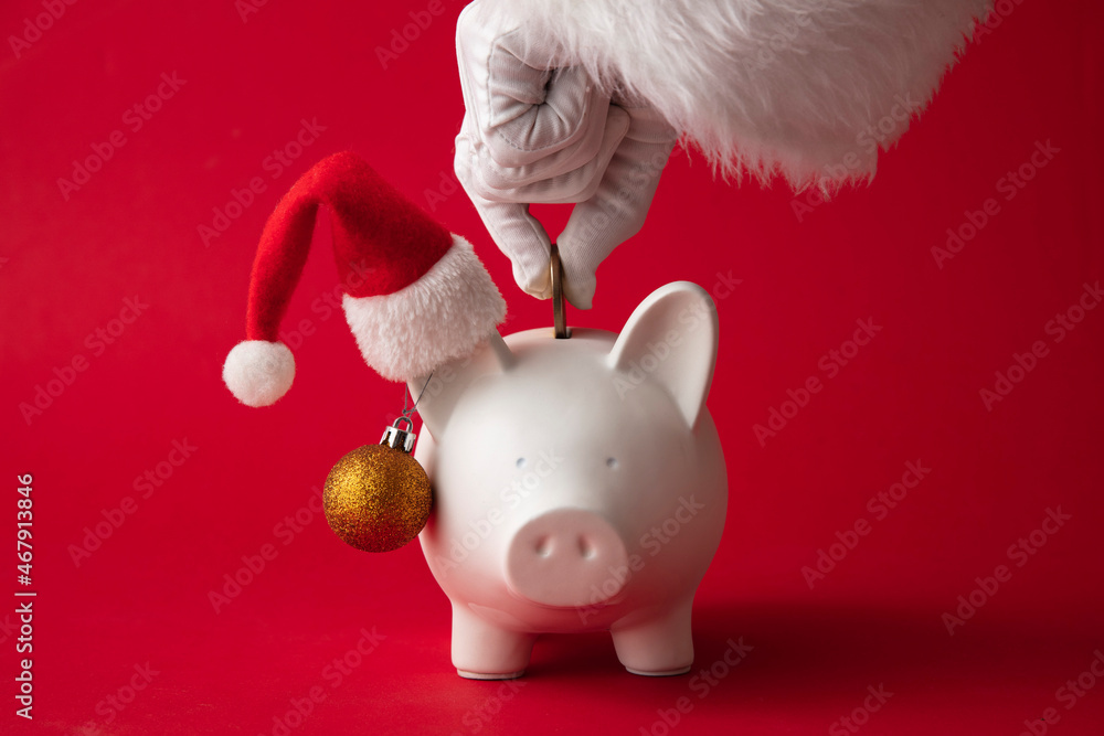 Santa Claus putting money into a Christmas piggy bank money box ...