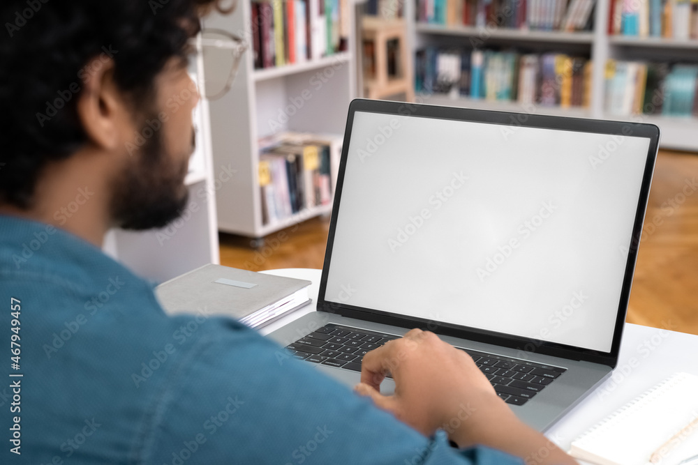 Indian teen male student working with laptop white screen mockup at ...
