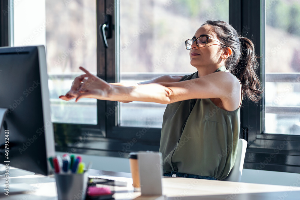 Tired businesswoman stretching body for relaxing while working with ...