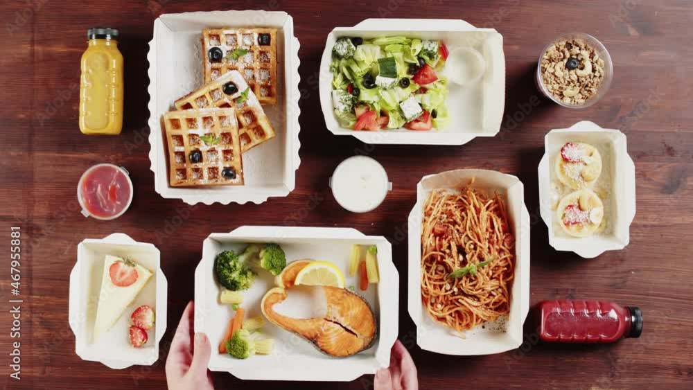 Food delivery top view. Putting lunch box with cooked salmon fish and ...