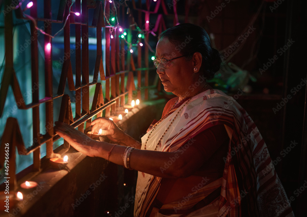A Hindu woman decorating her home with lighting earthen lamps (or diyas ...