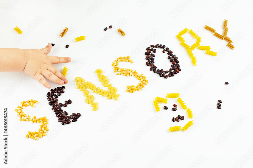 Sensory word written of popcorn, beans, pasta and children hands ...