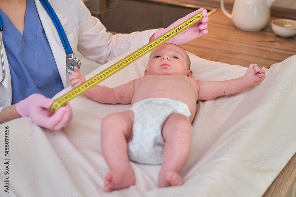Foto de Doctor measures the growth of a newborn baby. A nurse in ...