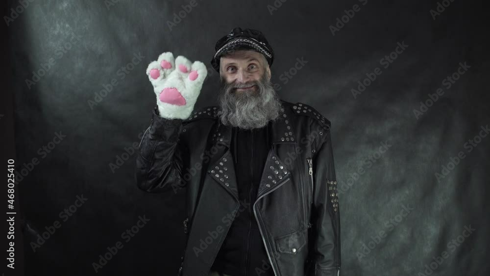 Bearded rockstar in leather jacket and cap smiling and waving to ...