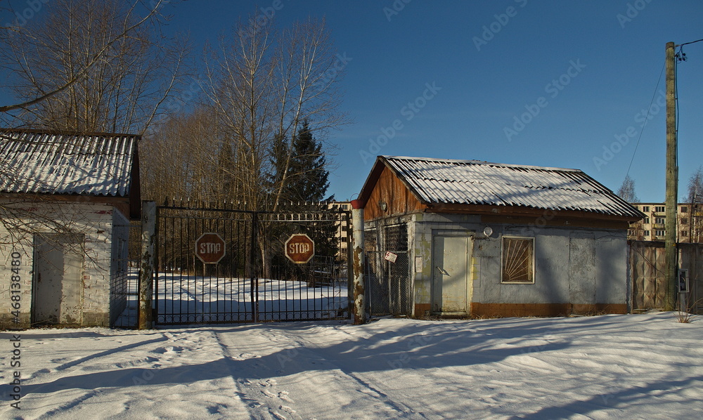 Closed metal gate with stop sign and guard houses in sunny winter day ...