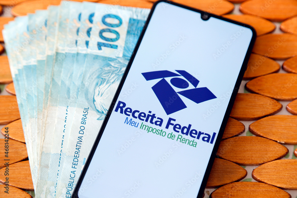 Receita Federal logo on mobile screen and Brazilian money bills Stock ...