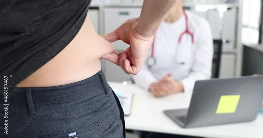 Male patient showing fat fold on abdomen at doctor appointment closeup ...