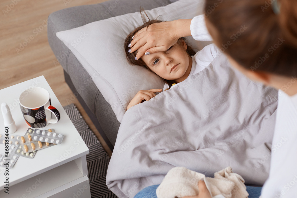 Foto de Cute little Caucasian girl lying under blanket feels bed ...