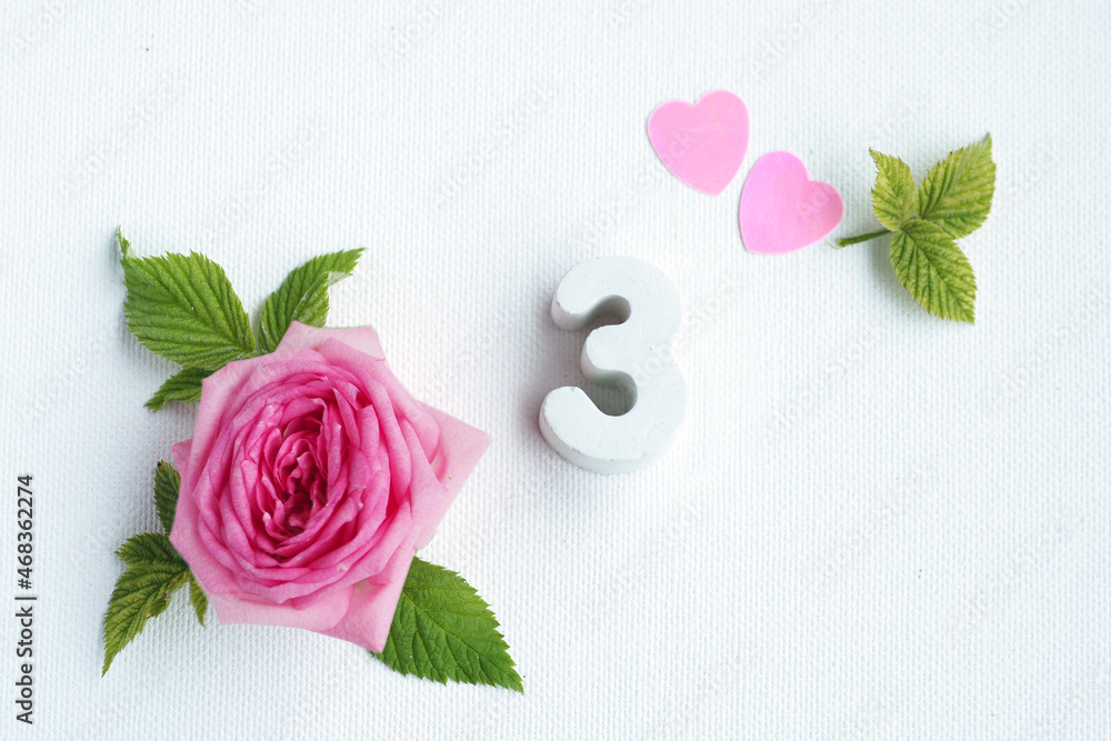 concrete number 3 and a beautiful rose with petals and hearts on a ...