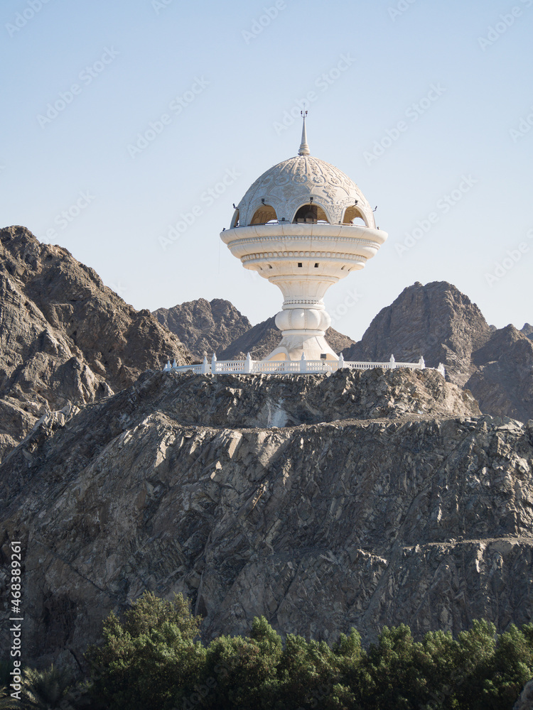 View to the Riyam Park monument dome through the palm leaves. Muscat ...