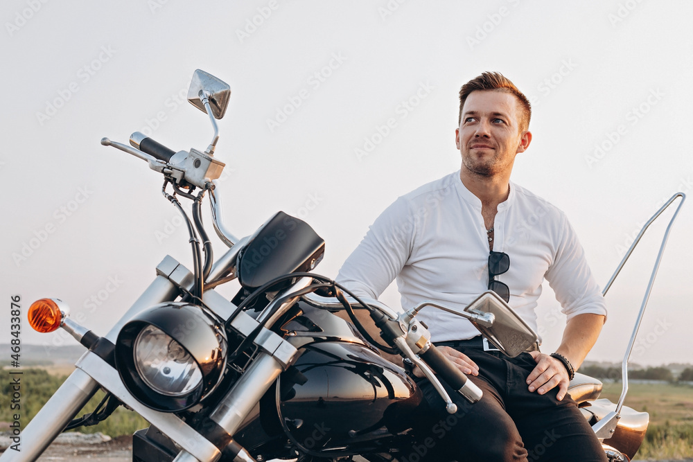 Stylish young attractive guy is sitting on a motorcycle. A nice young ...