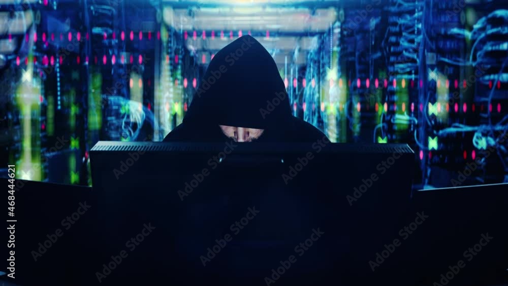 Male hacker typing on keyboard in server room, hacking into system ...