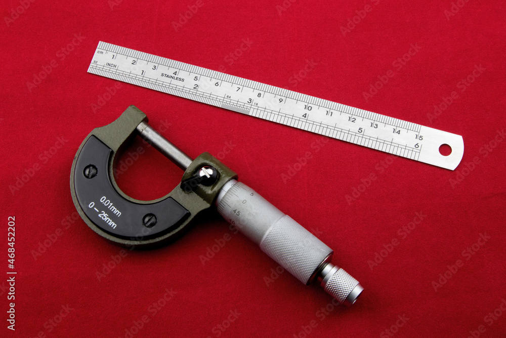 Engineering Micrometer and Steel Ruler on a Red Table Surface Stock ...