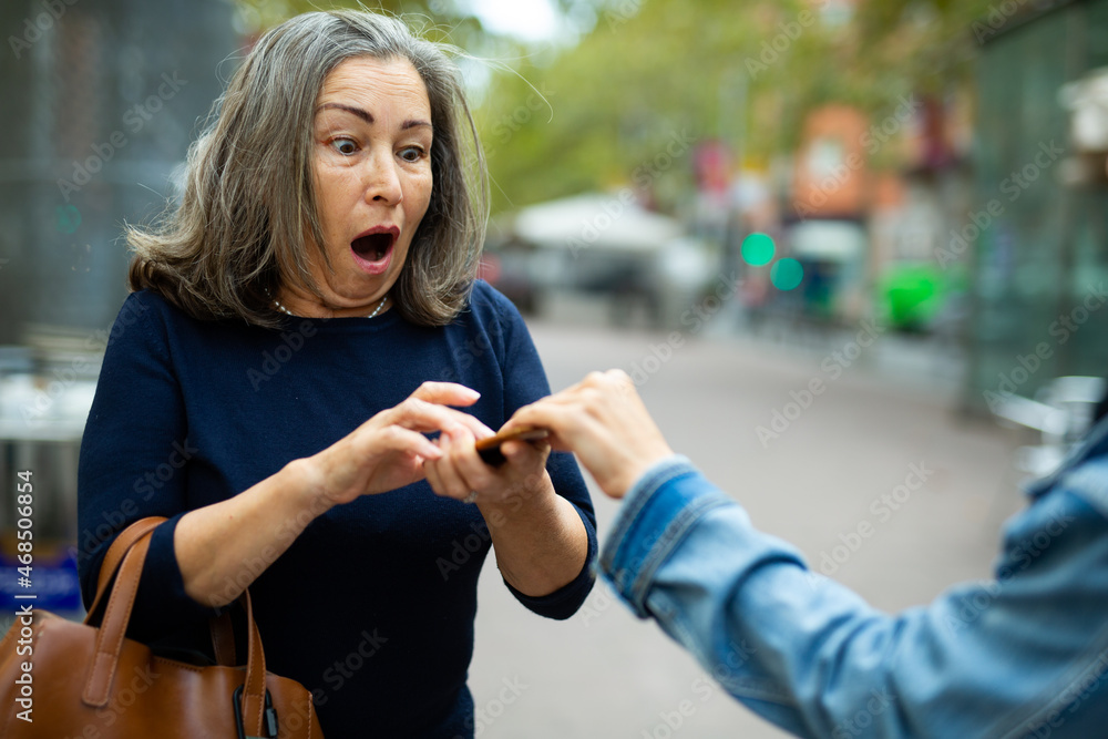 Foto de Street theft concept. Young female thief trying to snatch ...