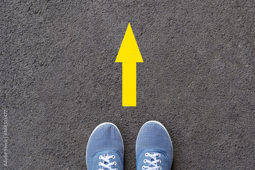 Feet and arrows on road. Direction arrow on asphalt ground, feet and ...