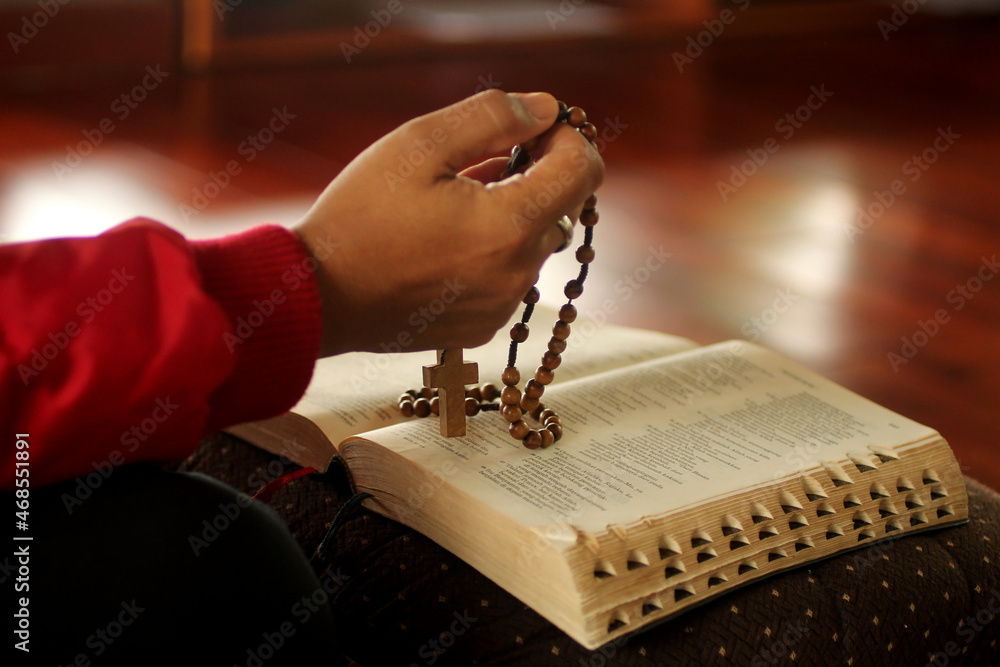 Person with a rosary. Religious young woman praying rosary on a bible ...