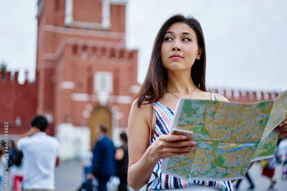 Contemplative Asian tourist with travel map thinking about route ...