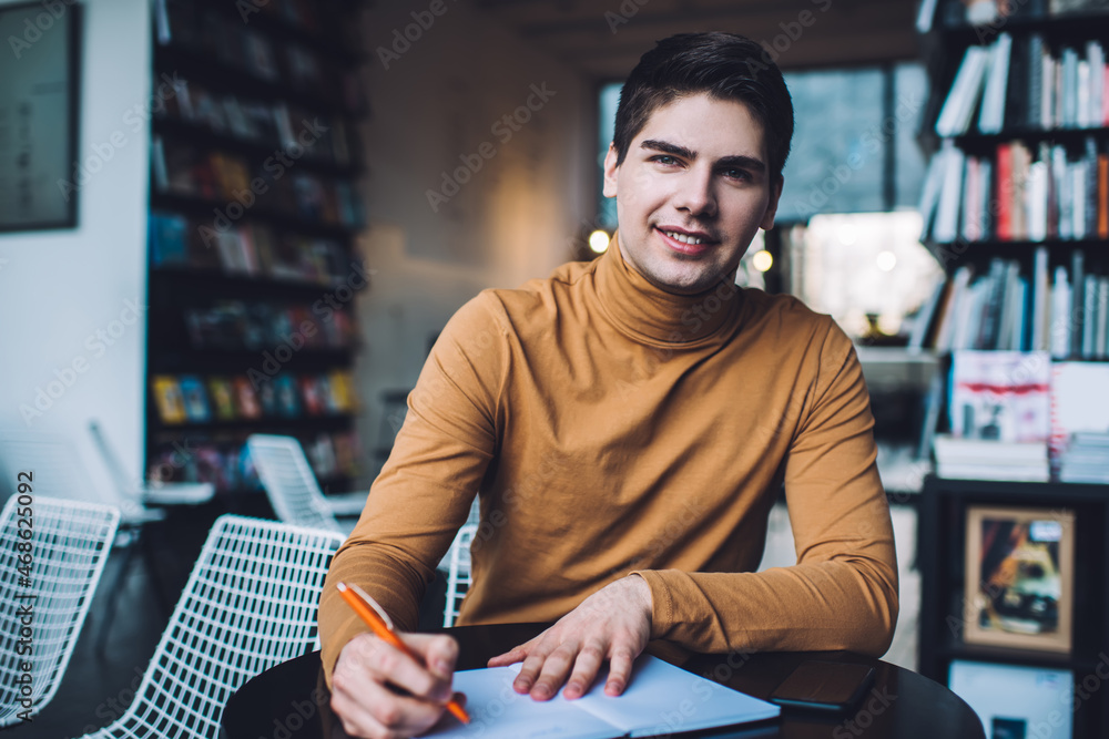Content man sitting in library with notebook Stock Photo | Adobe Stock