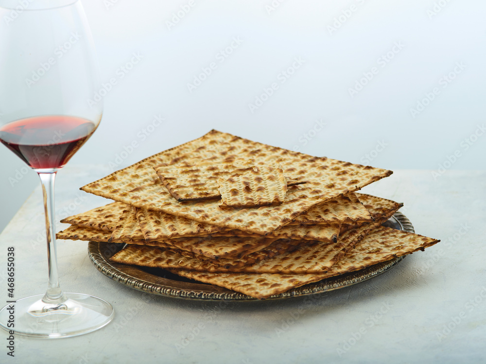 A stack of Jewish bread matzah and a glass with red wine on a white ...