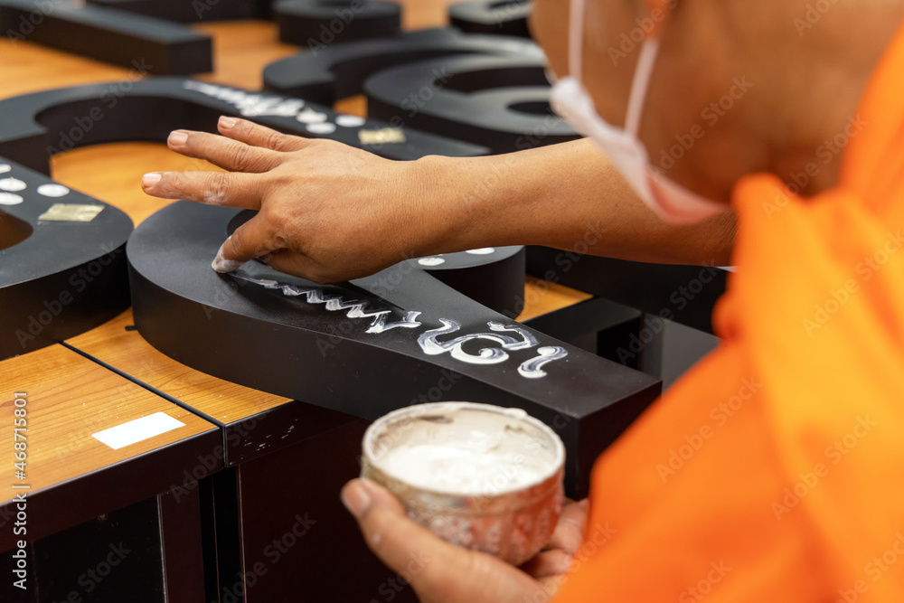 Thai monk to bless by making marks on the sign with sachet powder for ...