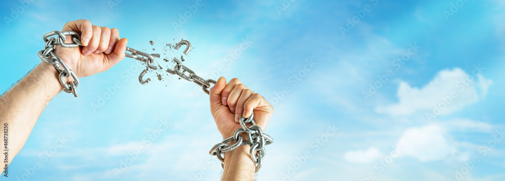 Male hands break the chains on blue sky background with copy space ...