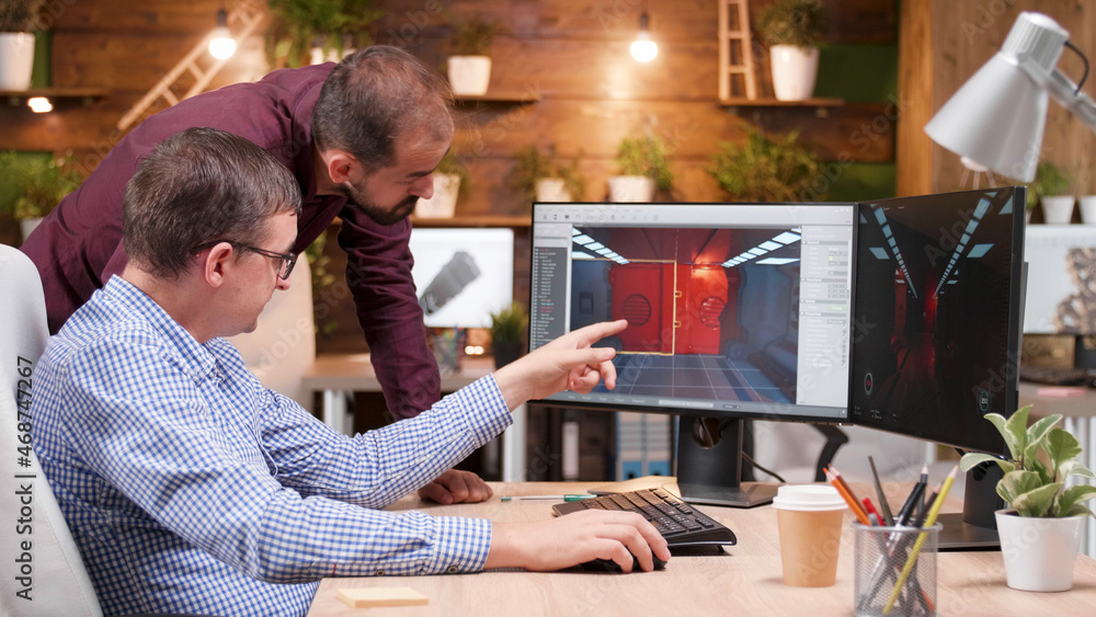 Graphic designer in gaming industry talking detail with his colleague ...