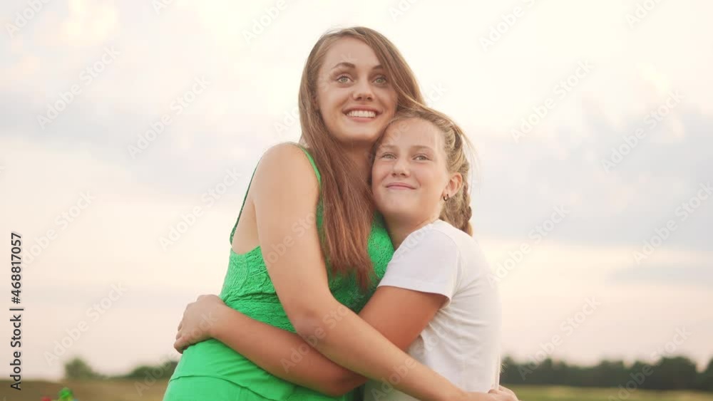 two sisters of a teenager hugging in nature in the park. happy family ...