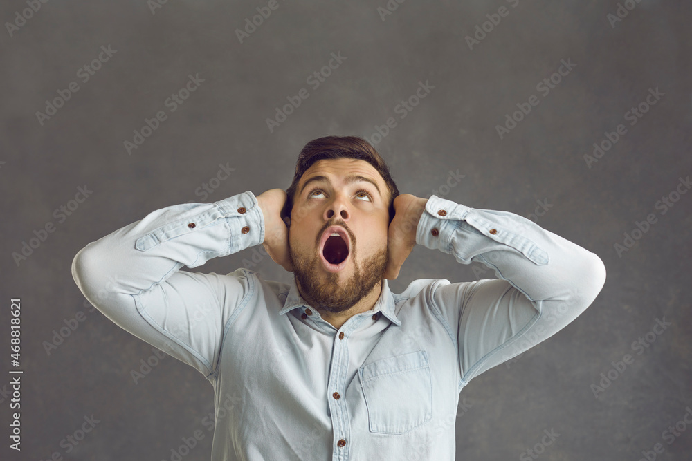 Studio portrait of surprised young man looking up and touching head ...