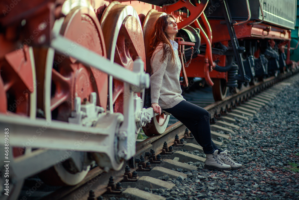 A beautiful young woman sits at the wheels of a large vintage train at ...