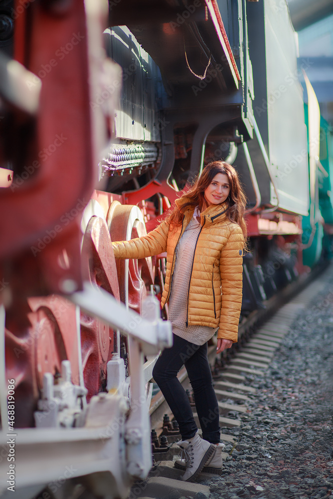 A beautiful young woman sits at the wheels of a large vintage train at ...