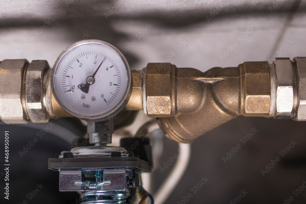 there is a pipe with water on the tiled wall. a water meter is also ...