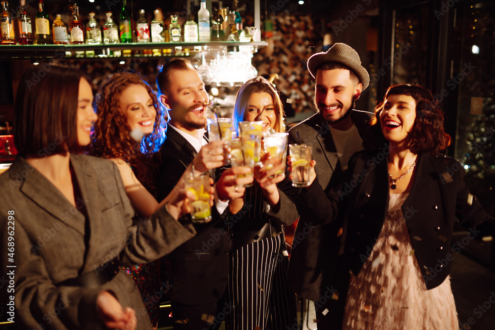 Cheering and drinking cocktails. Group of people partying in a ...