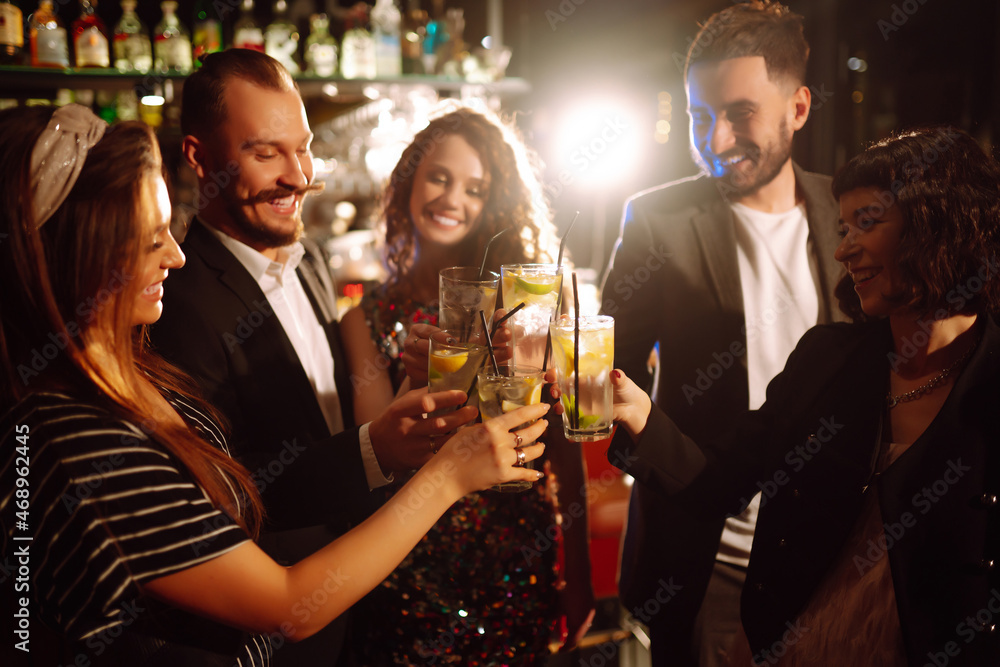 Cheering and drinking cocktails. Group of people partying in a ...