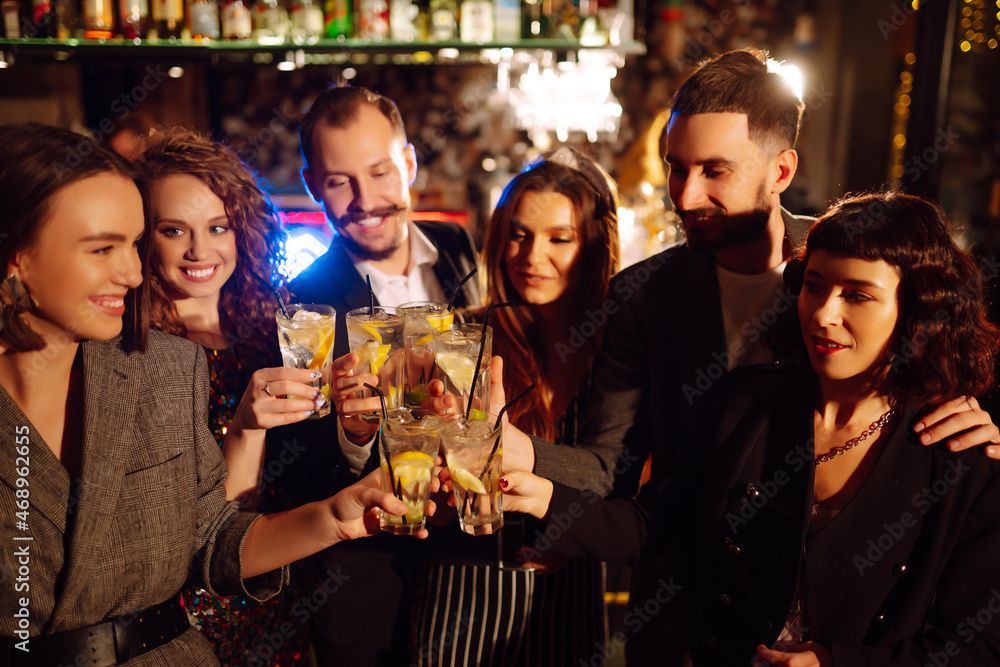 Cheering and drinking cocktails. Group of people partying in a ...