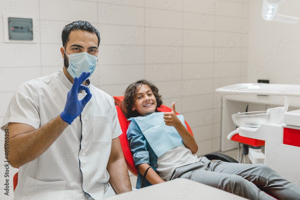 Smiling confident male dentist showing okay gesture while his patient ...