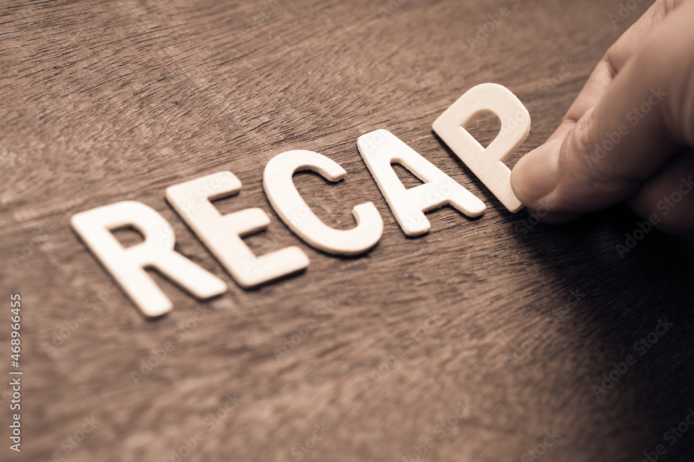 Hand arrange the wooden small alphabets as RECAP word on wood table ...